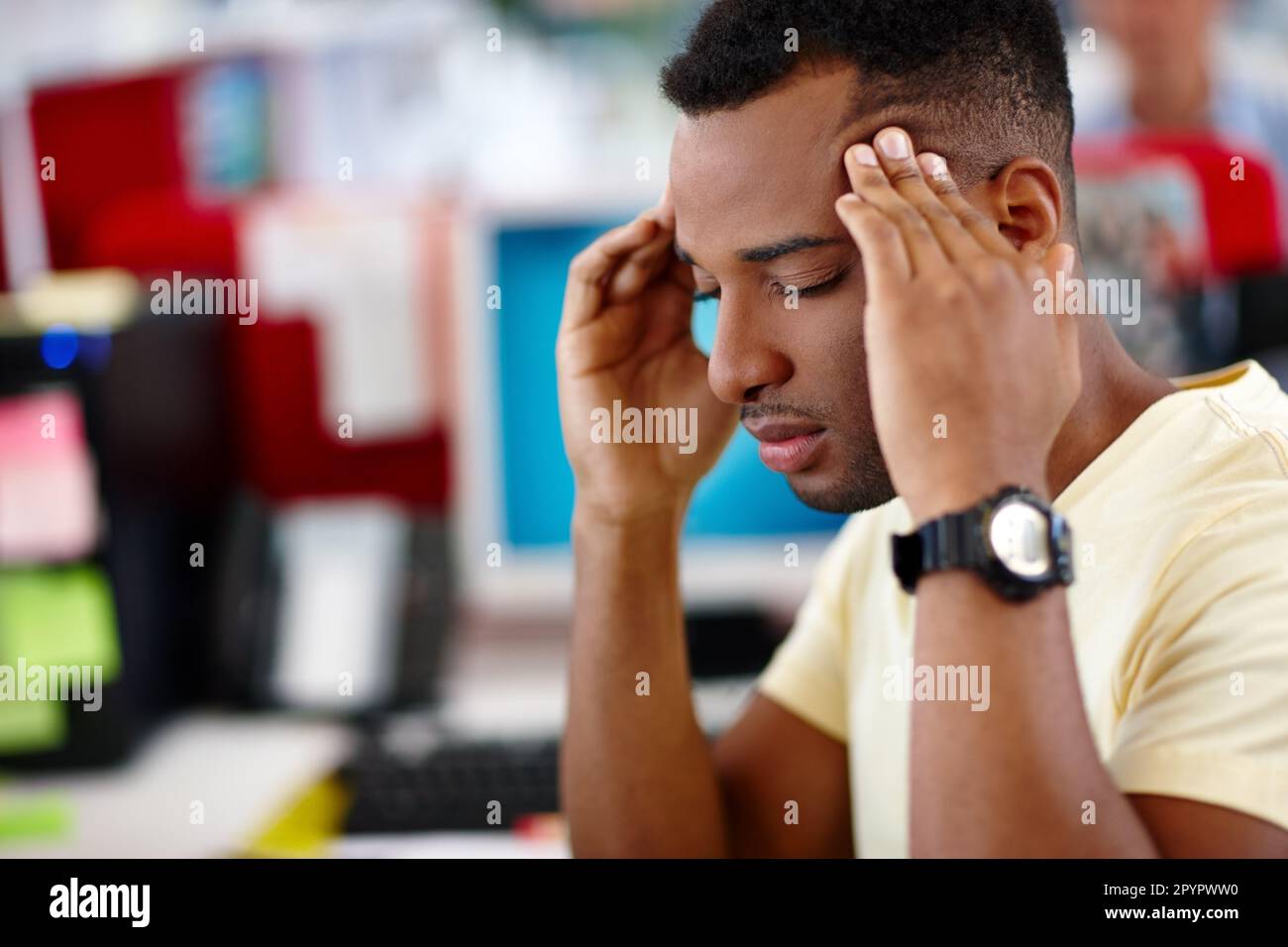 Its too much. a handsome young man suffering from a headache at work ...
