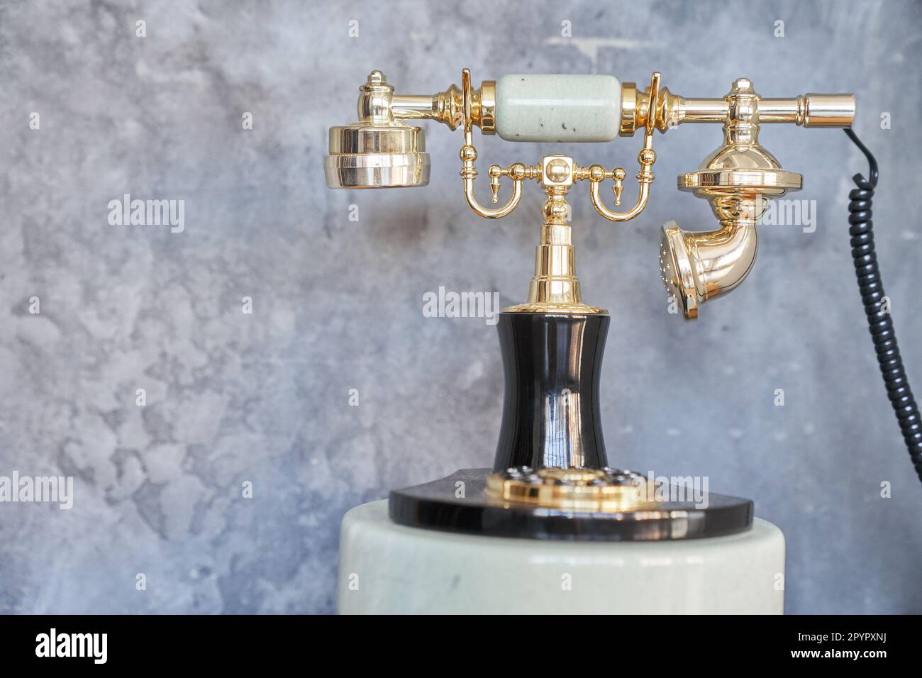 Antique gold phone with original handset, on a gray wall background ...