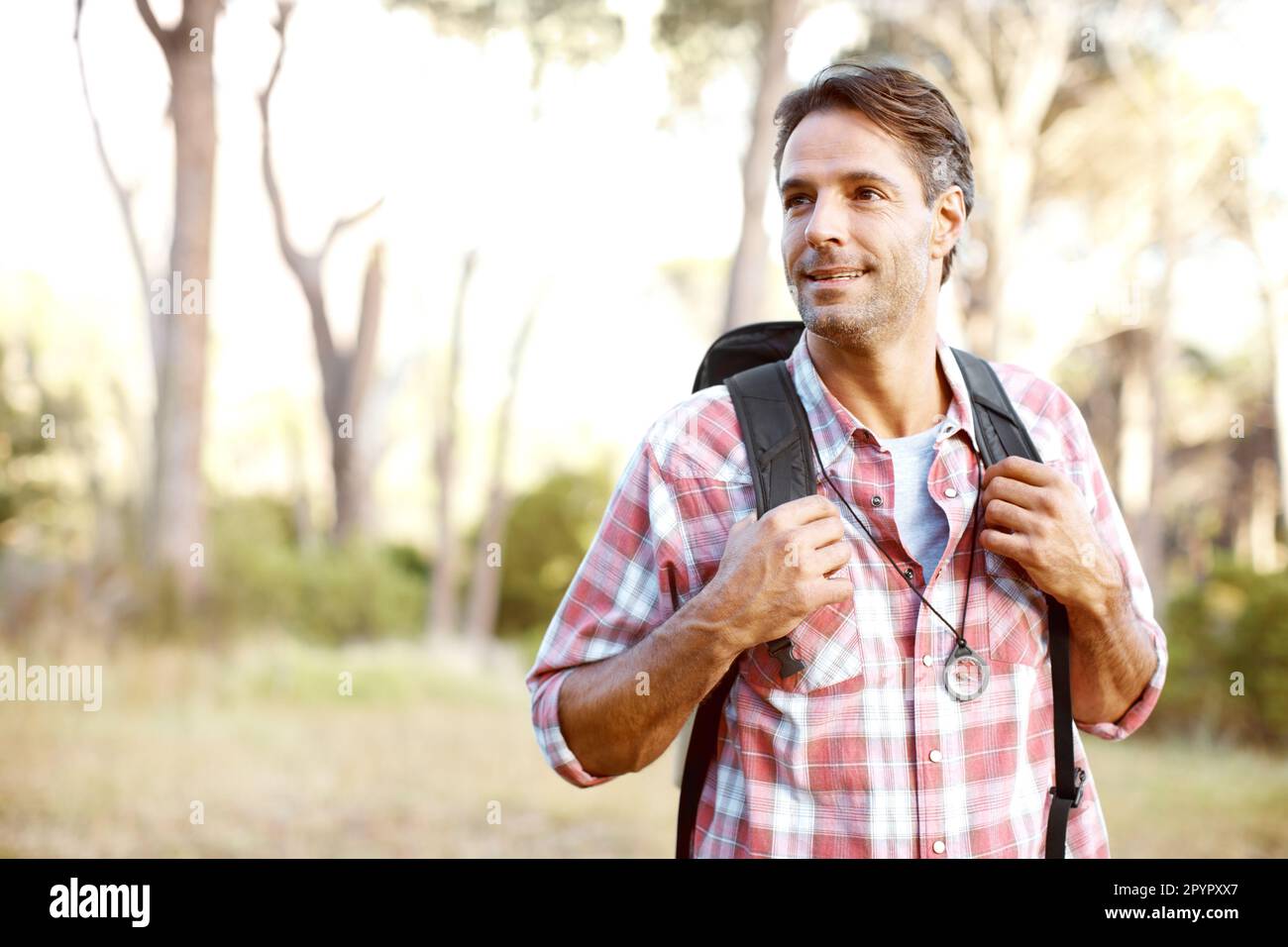 I love the outdoors. A handsome young man wearing a backpack while ...
