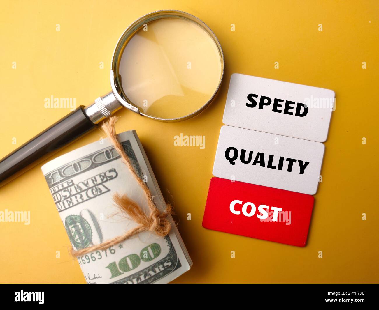 Top view banknote and magnifying glass with the word SPEED QUALITY COST ...