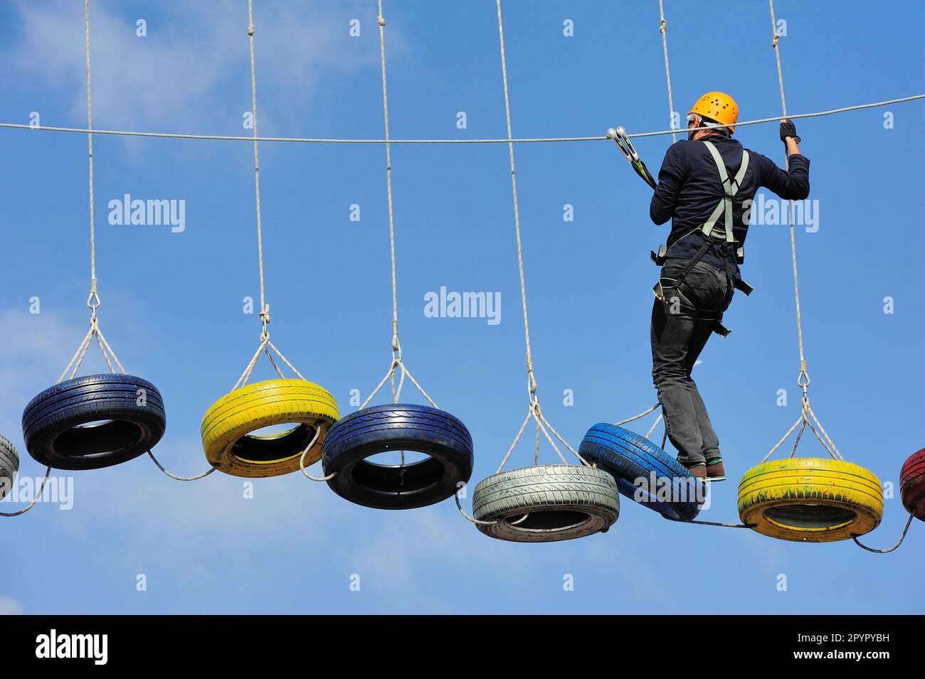 The man walking and holding exercises on multicolored painted car tires ...