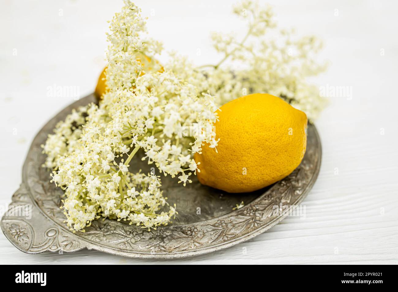 A transparent glass with a slice of lemon and a bouquet of elderberry ...