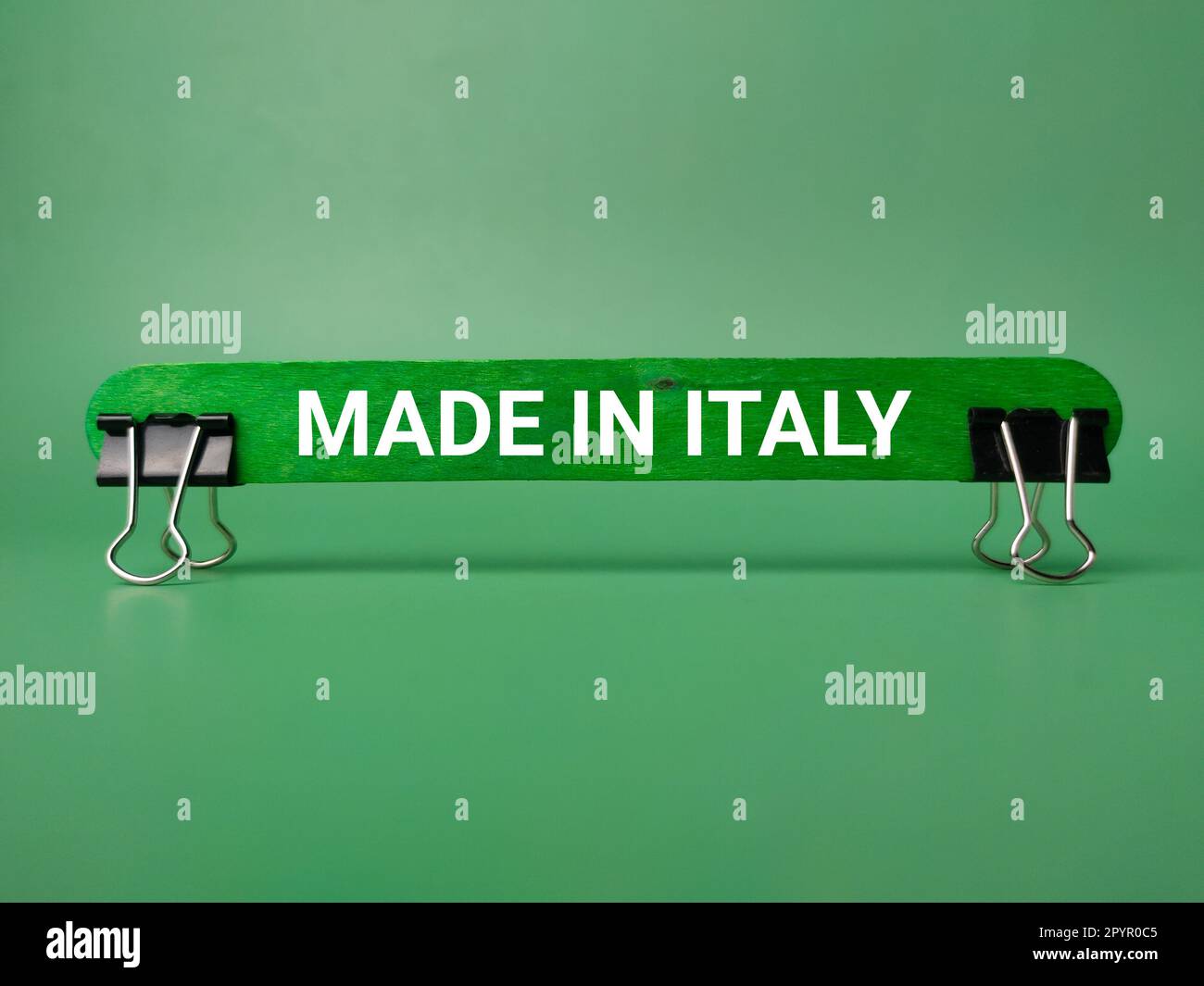 Paper clips and wooden stick with the word MADE IN ITALY on a green ...