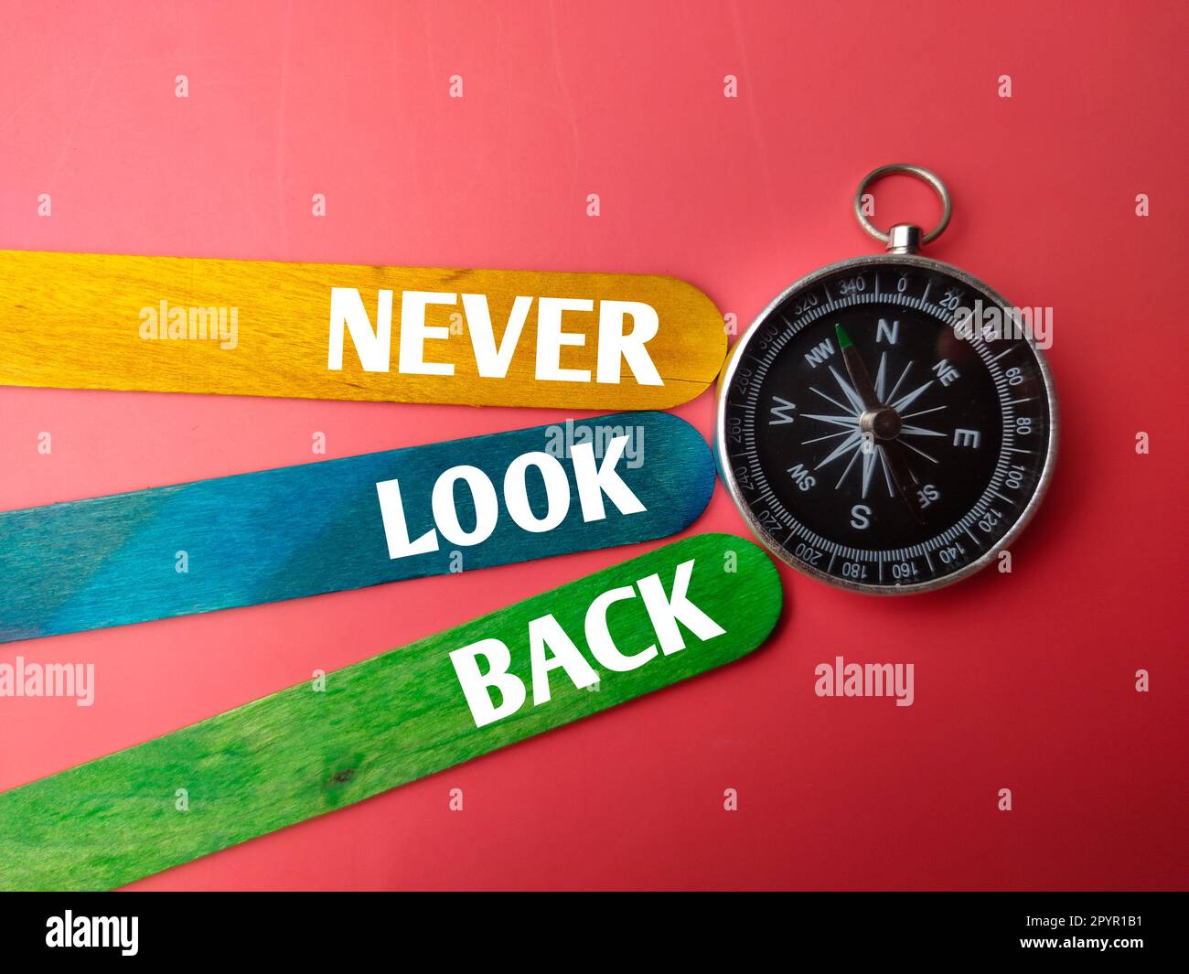 Wooden stick and compass with the word NEVER LOOK BACK on red ...