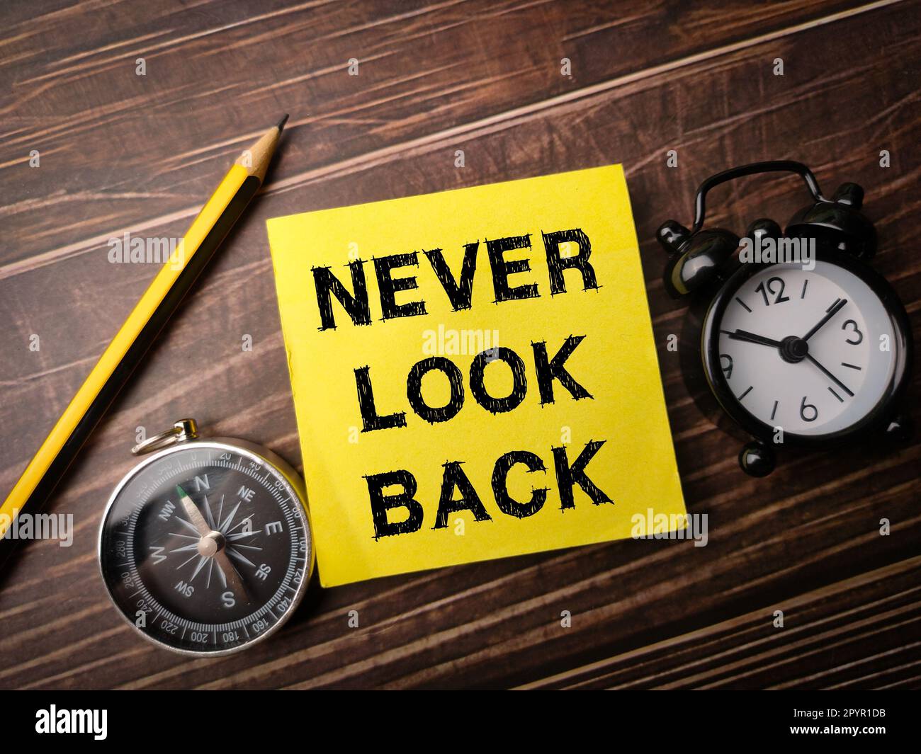 Pencil and compass with the word NEVER LOOK BACK on wooden background ...