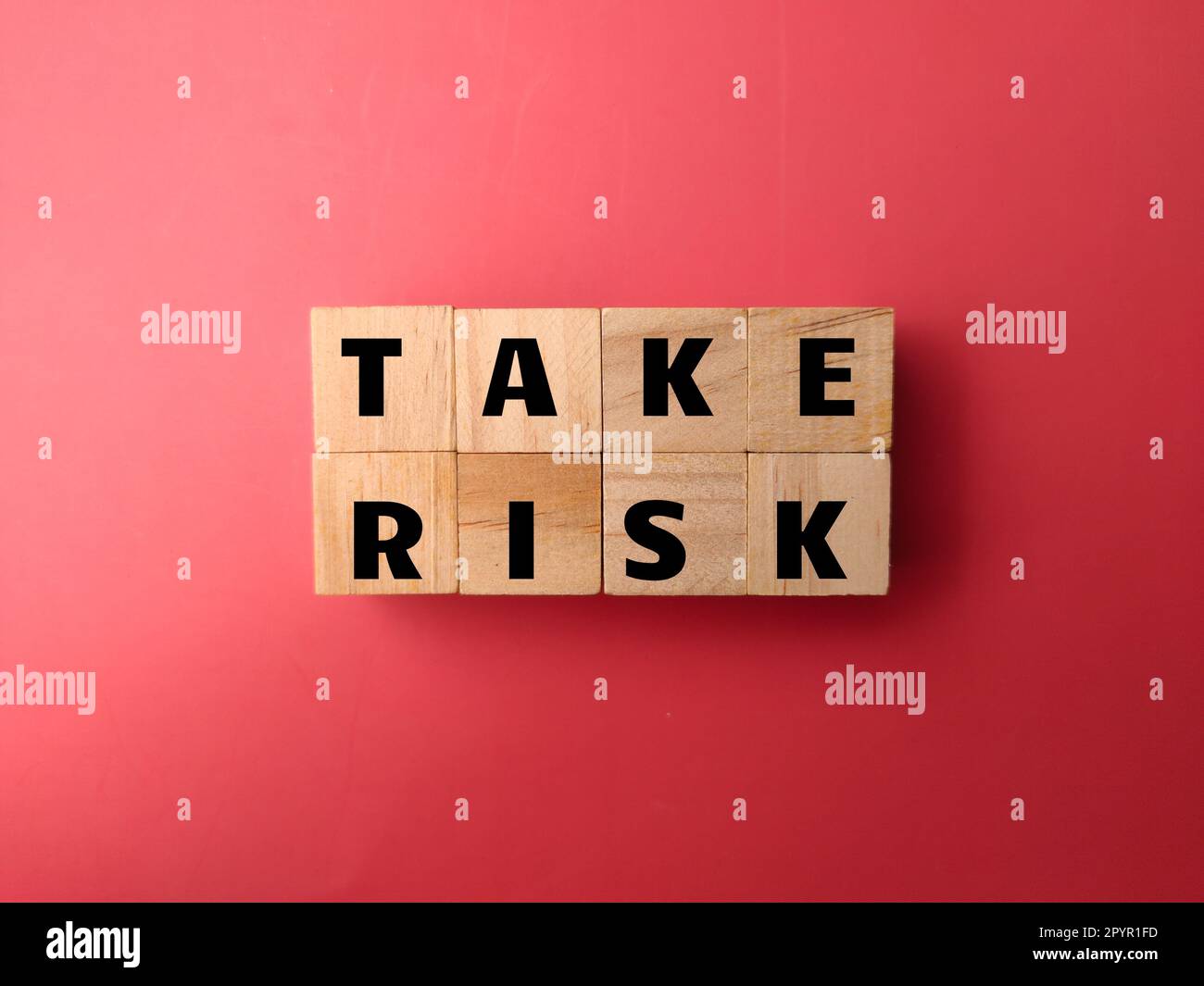 Wooden cube with the word TAKE RISK on a red background Stock Photo - Alamy
