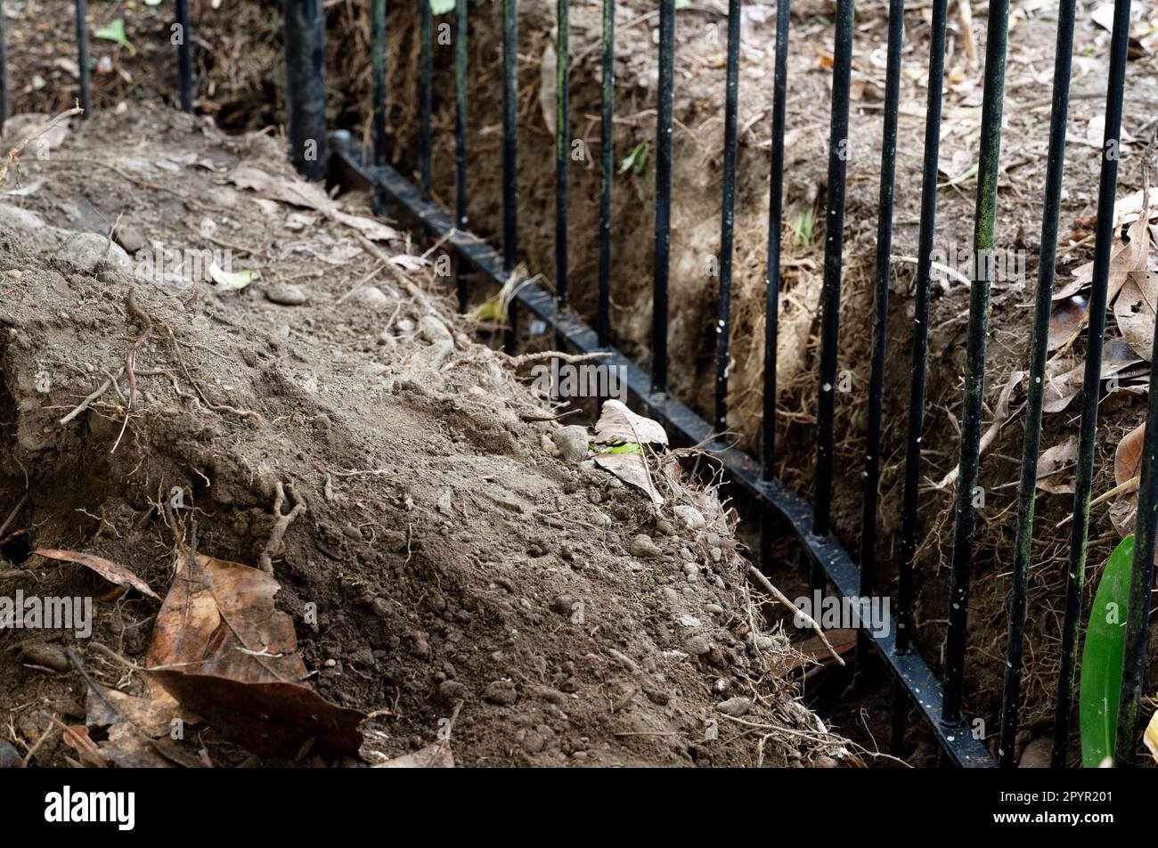 Construction of a black steel garden boundary fence, a trench has been ...