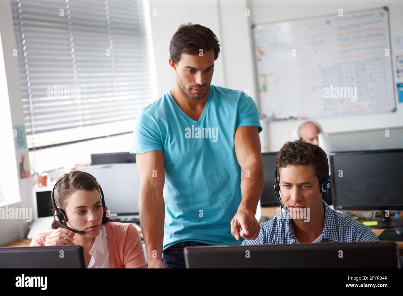 Quality control. A handsome man standing and pointing at a computer ...