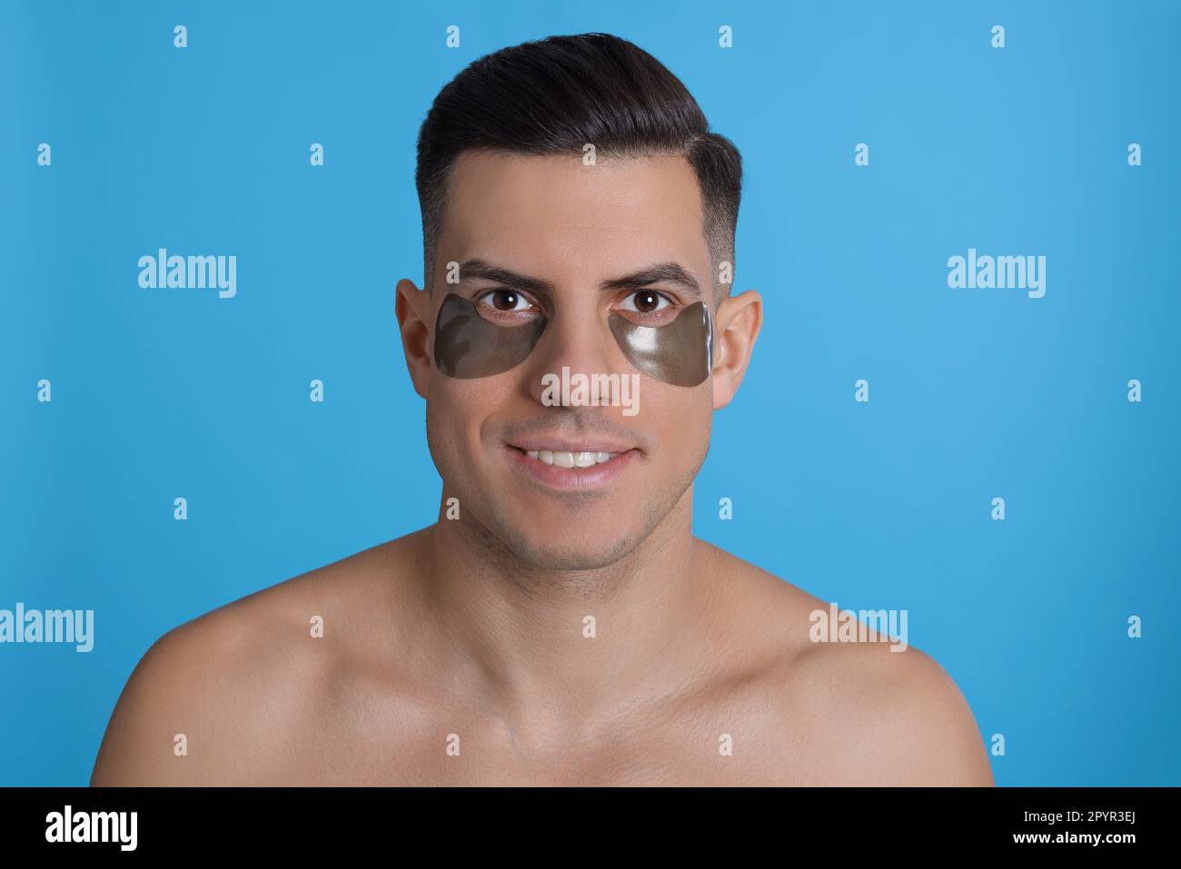 Man with dark under eye patches on light blue background Stock Photo ...