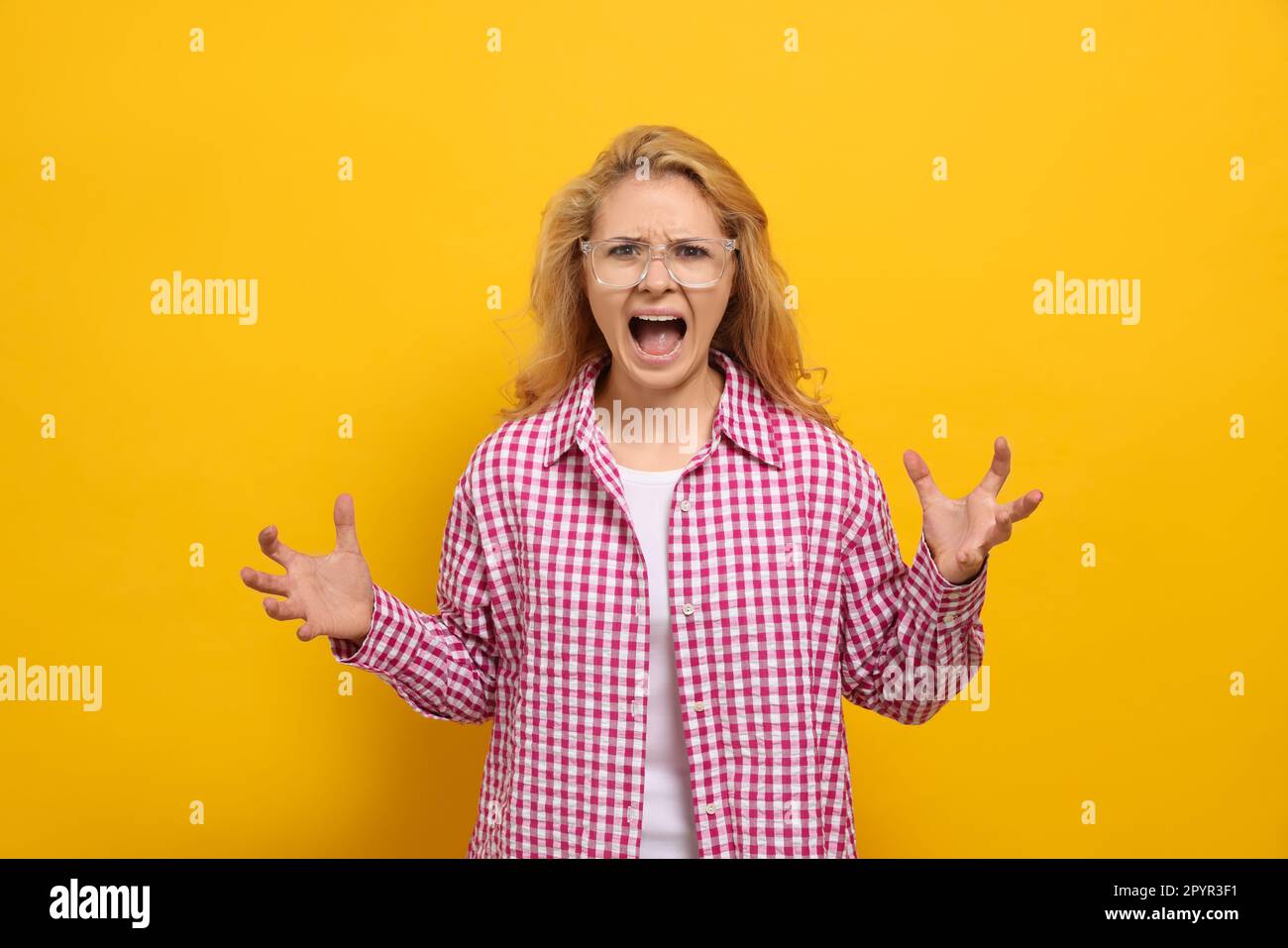 Aggressive young woman screaming with rage on yellow background Stock ...