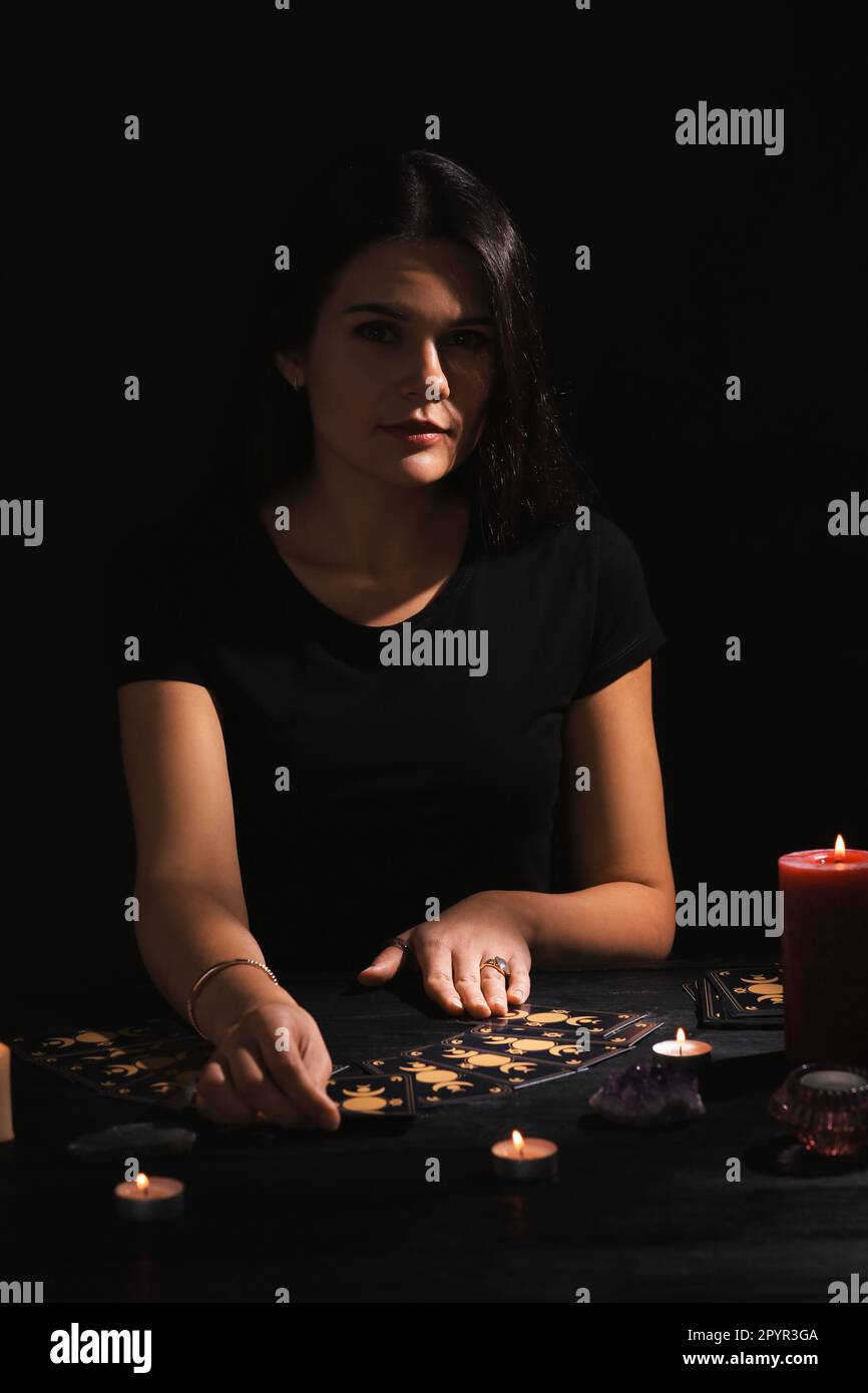 Soothsayer predicting future with tarot cards at table in darkness ...