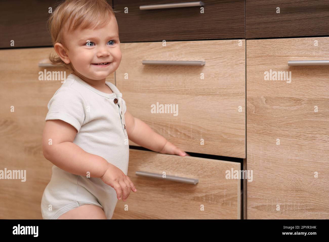 Little child exploring drawer indoors. Dangerous situation Stock Photo ...
