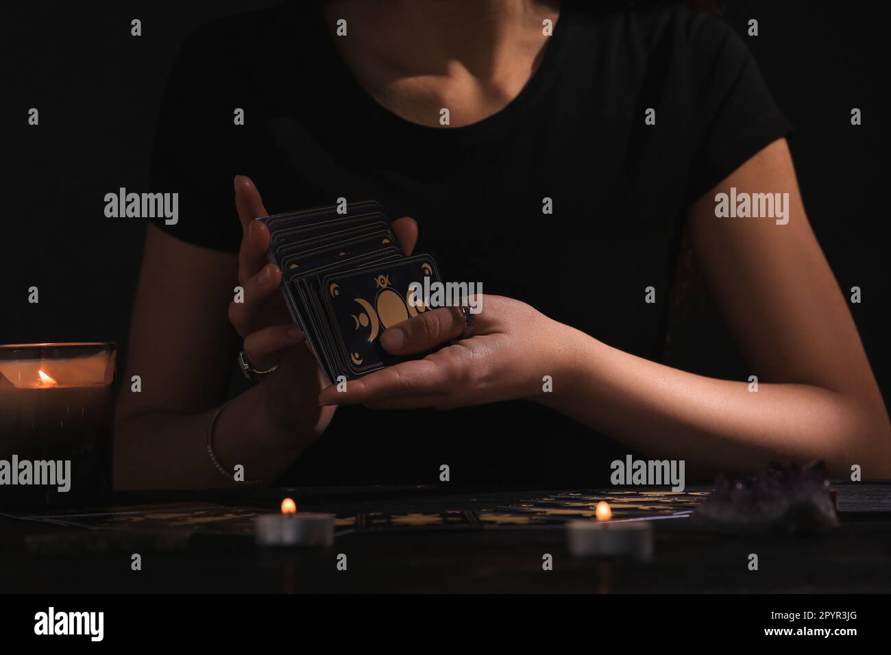 Soothsayer shuffling tarot cards at table in darkness. Fortune telling ...