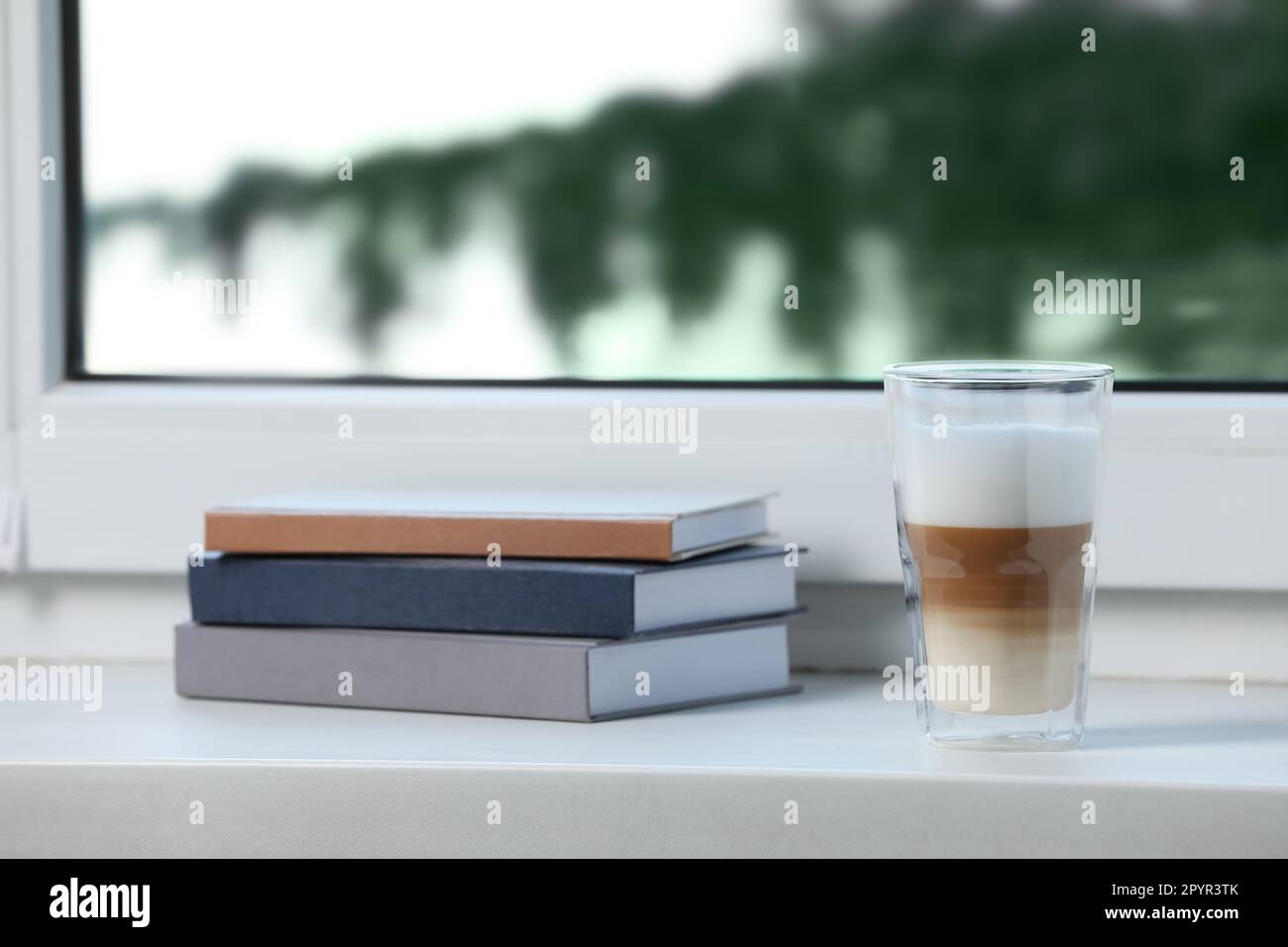 Books and glass with latte on white window sill Stock Photo - Alamy