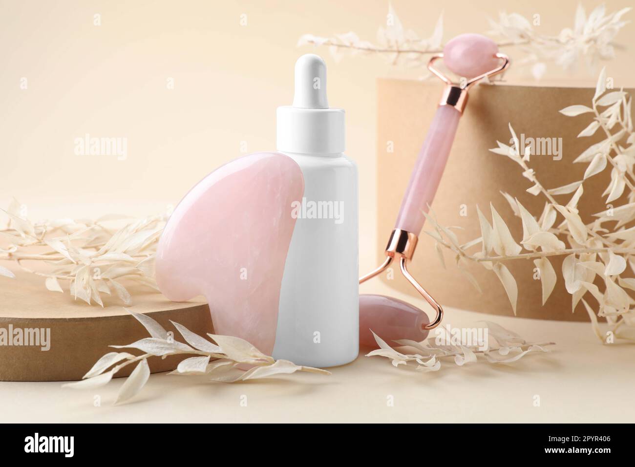Composition with rose quartz gua sha tool, facial roller and bottle of ...