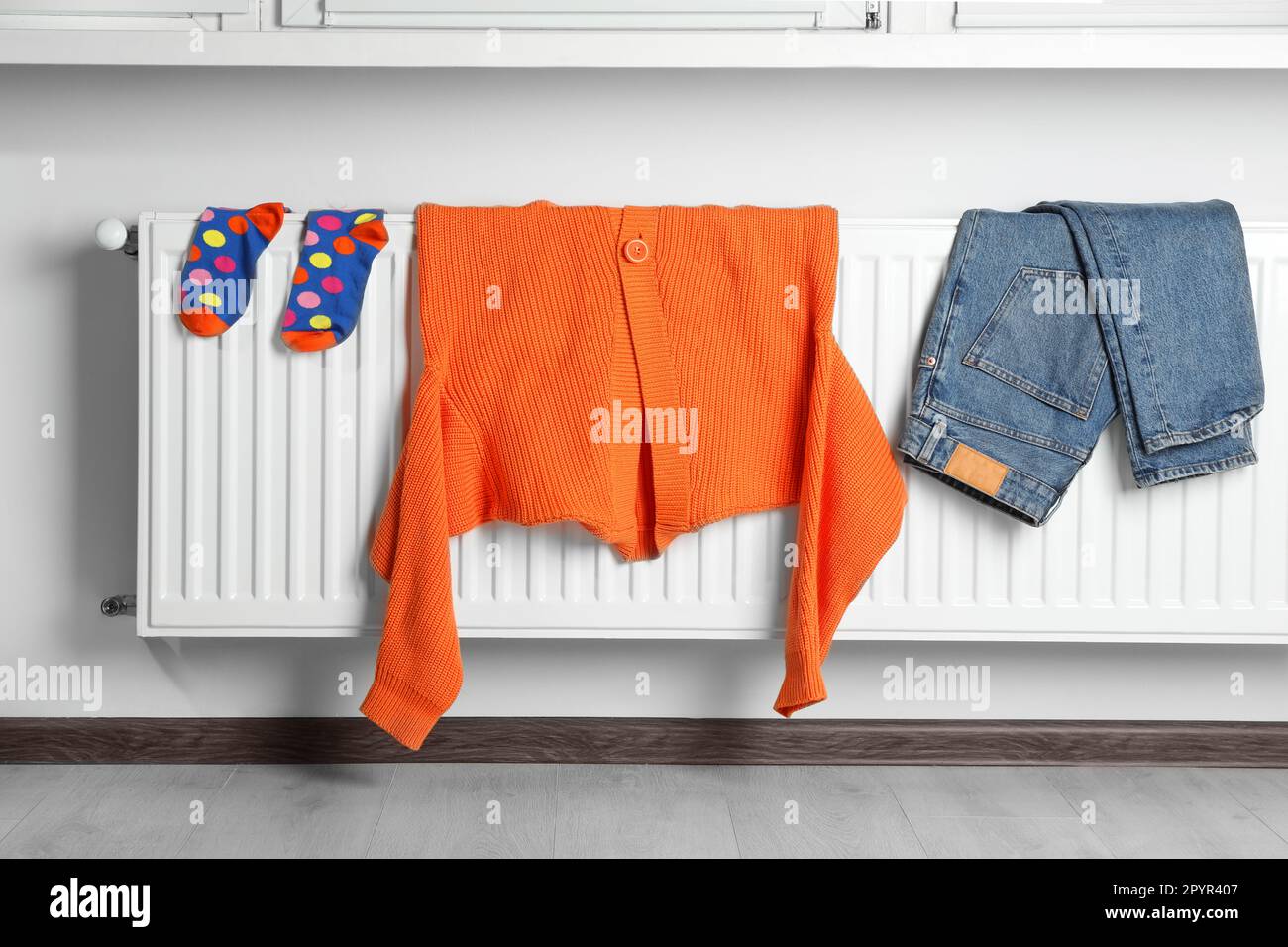 Clean clothes hanging on white radiator in room Stock Photo - Alamy