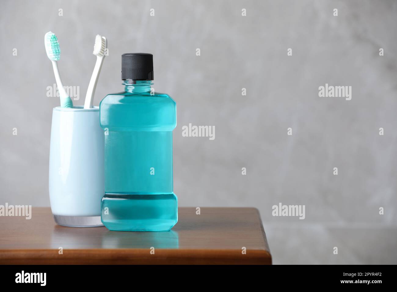 Bottle of mouthwash and toothbrushes on wooden table, space for text ...