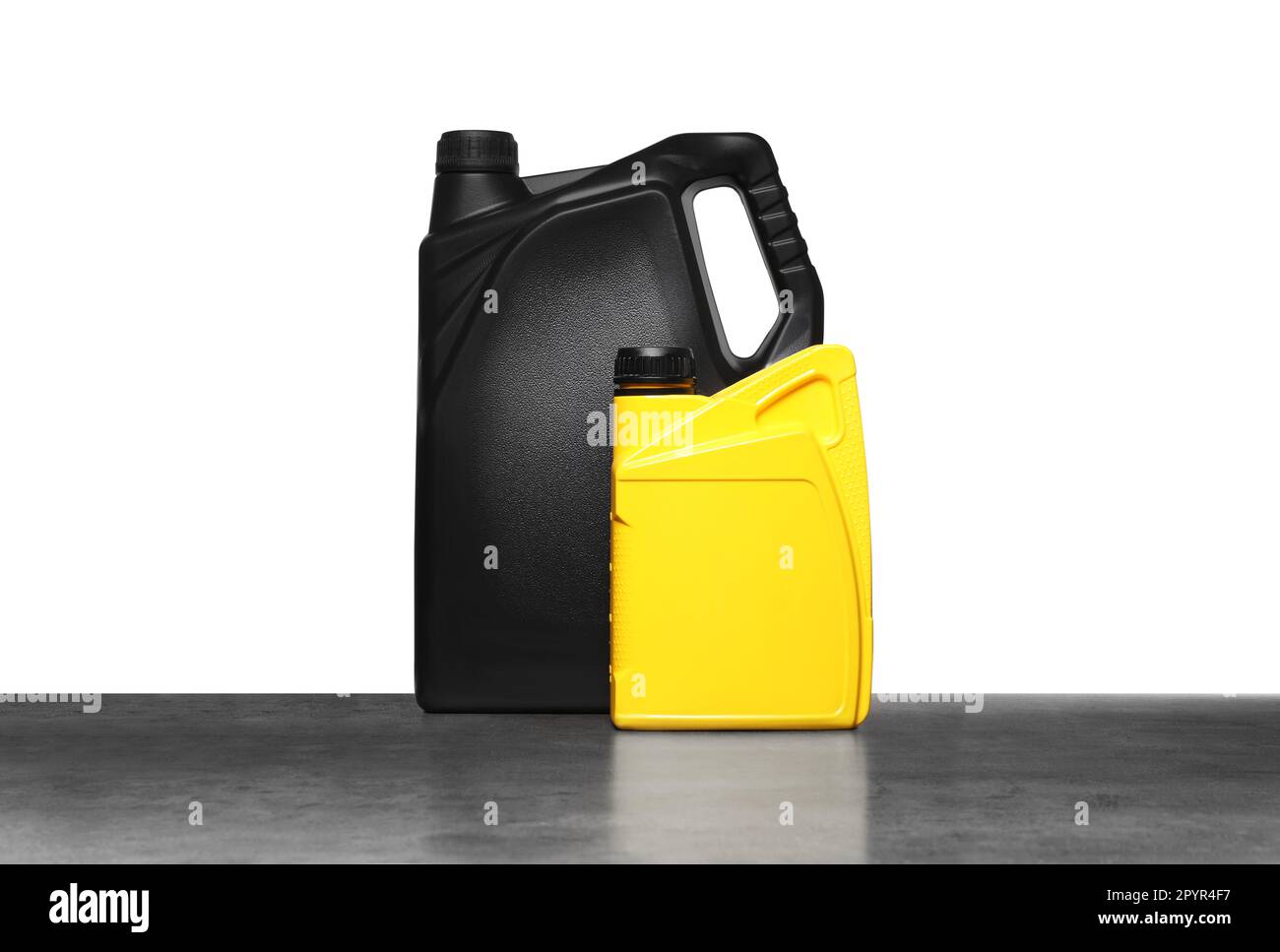 Motor oil in different containers on grey table against white ...