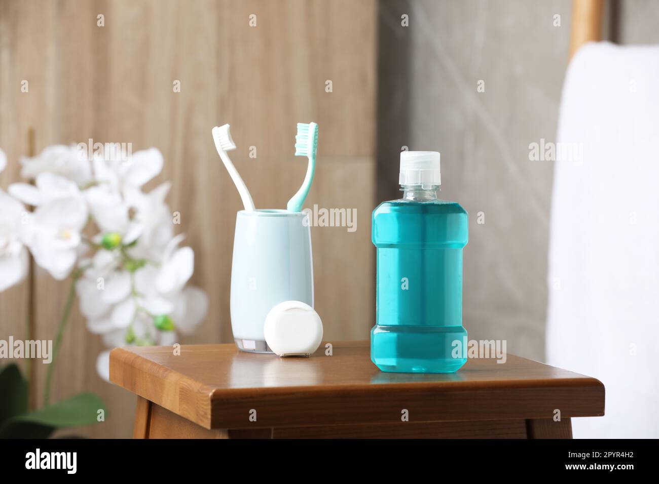 Bottle of mouthwash, toothbrushes and dental floss on wooden table in ...