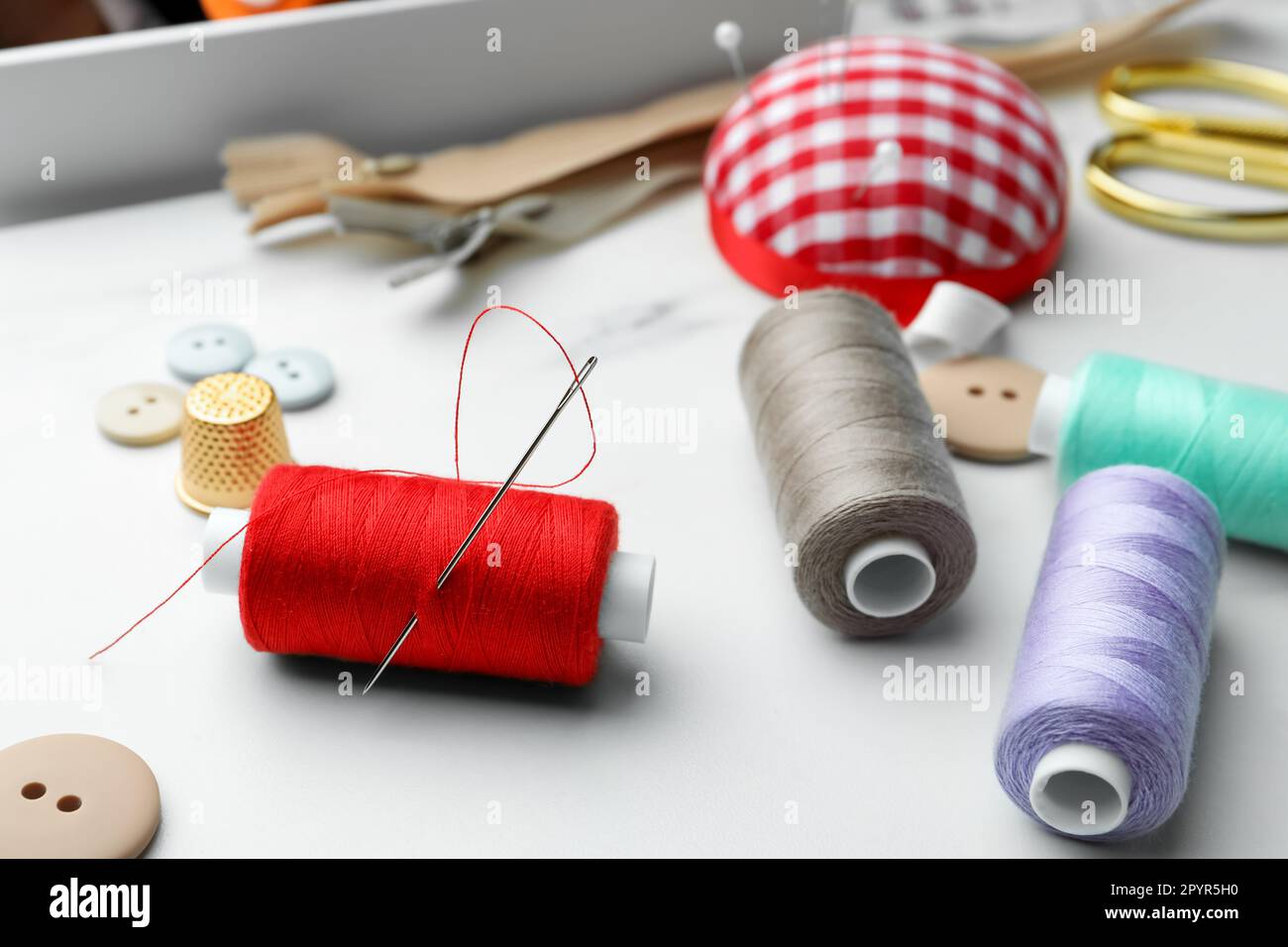 Threads and other sewing supplies on white marble table Stock Photo - Alamy