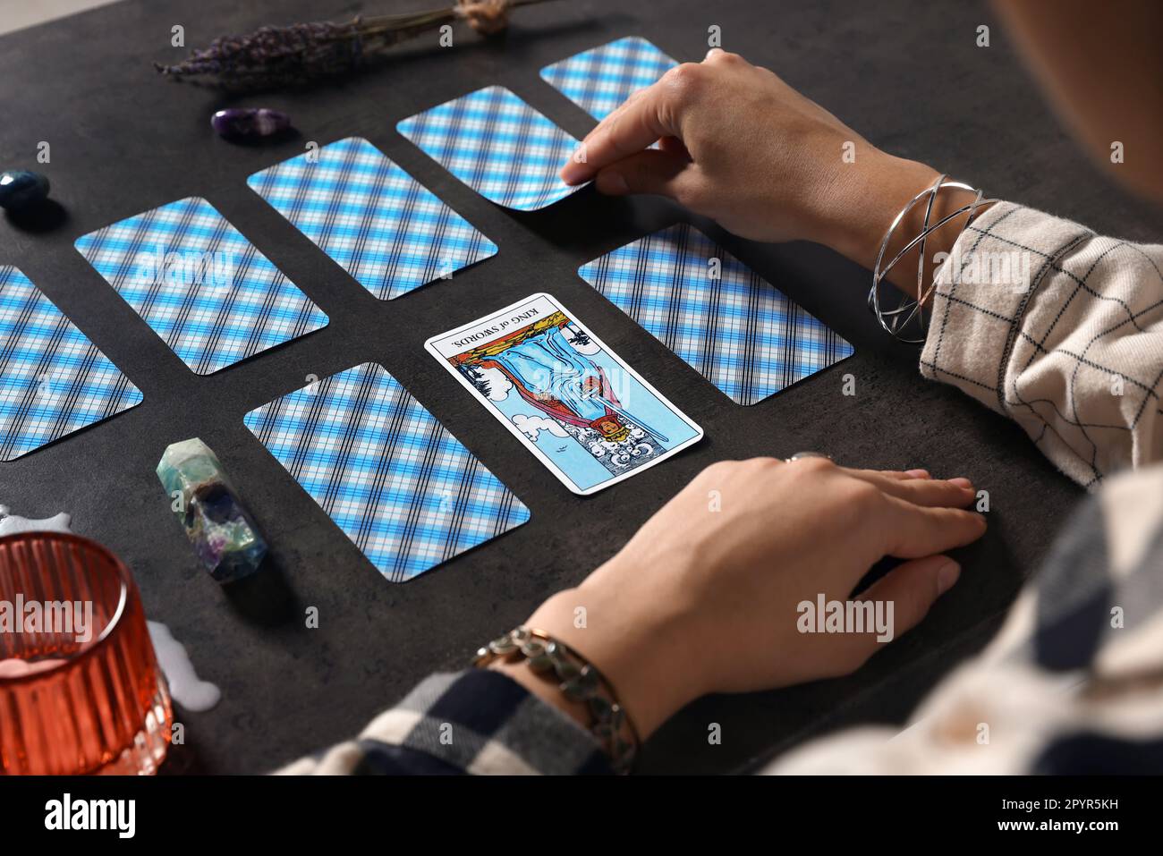 Fortune teller predicting future on spread of tarot cards at grey table ...