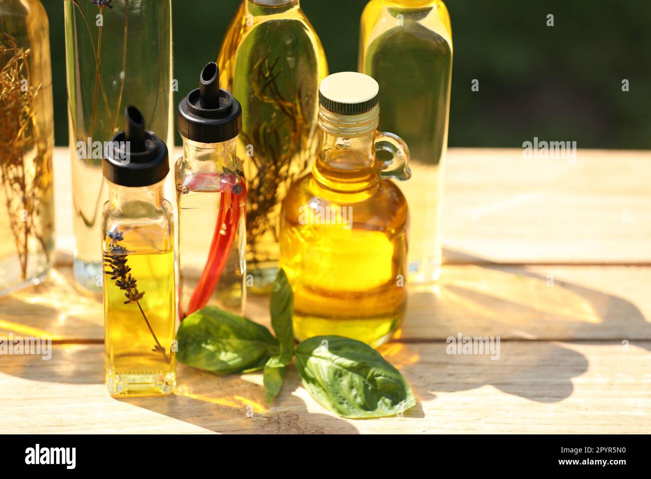 Many different cooking oils on wooden table against blurred green ...