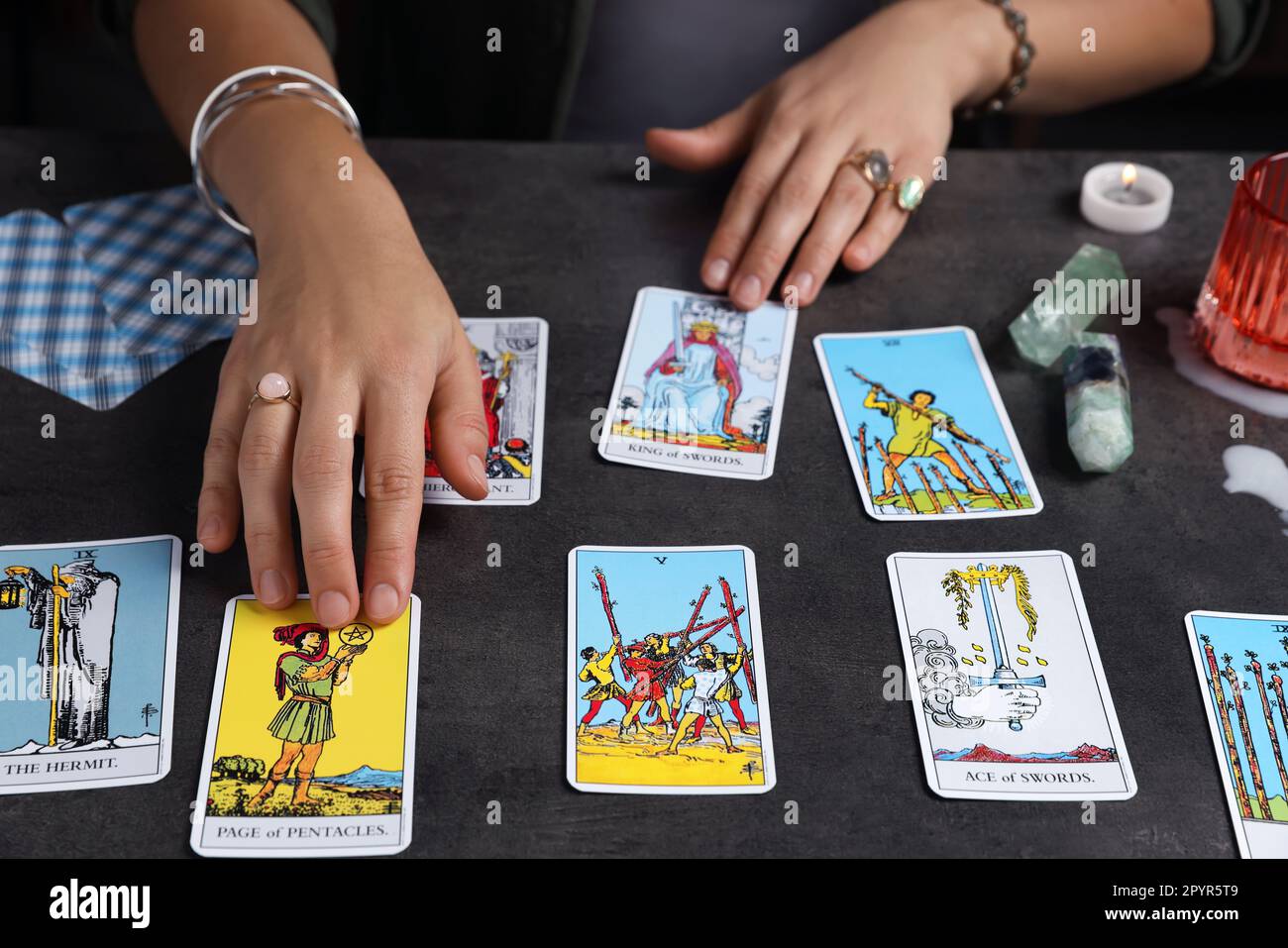 Fortune teller predicting future on spread of tarot cards at grey table ...