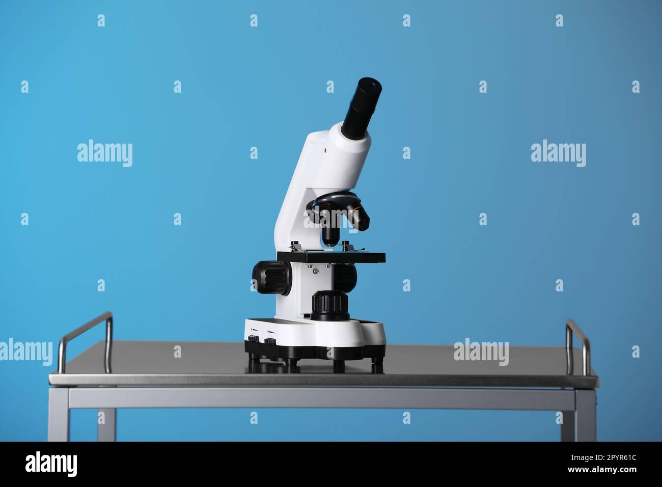 Modern microscope on metal table against blue background Stock Photo ...