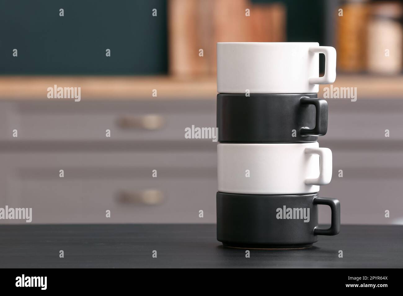 Stack of cups on black table in kitchen Stock Photo - Alamy