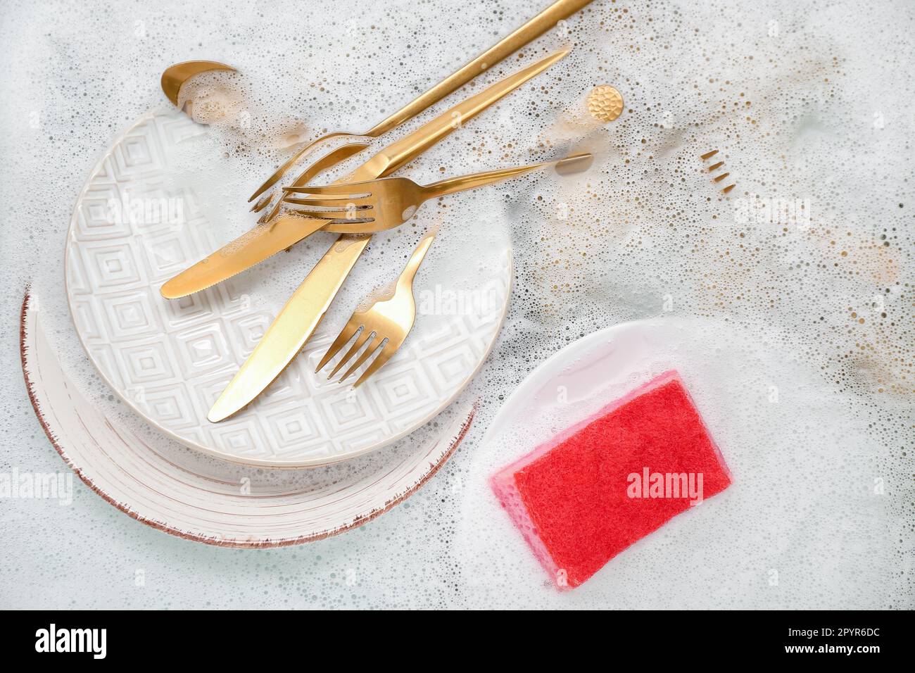 Cleaning sponge with dishes and foam in water, closeup Stock Photo - Alamy