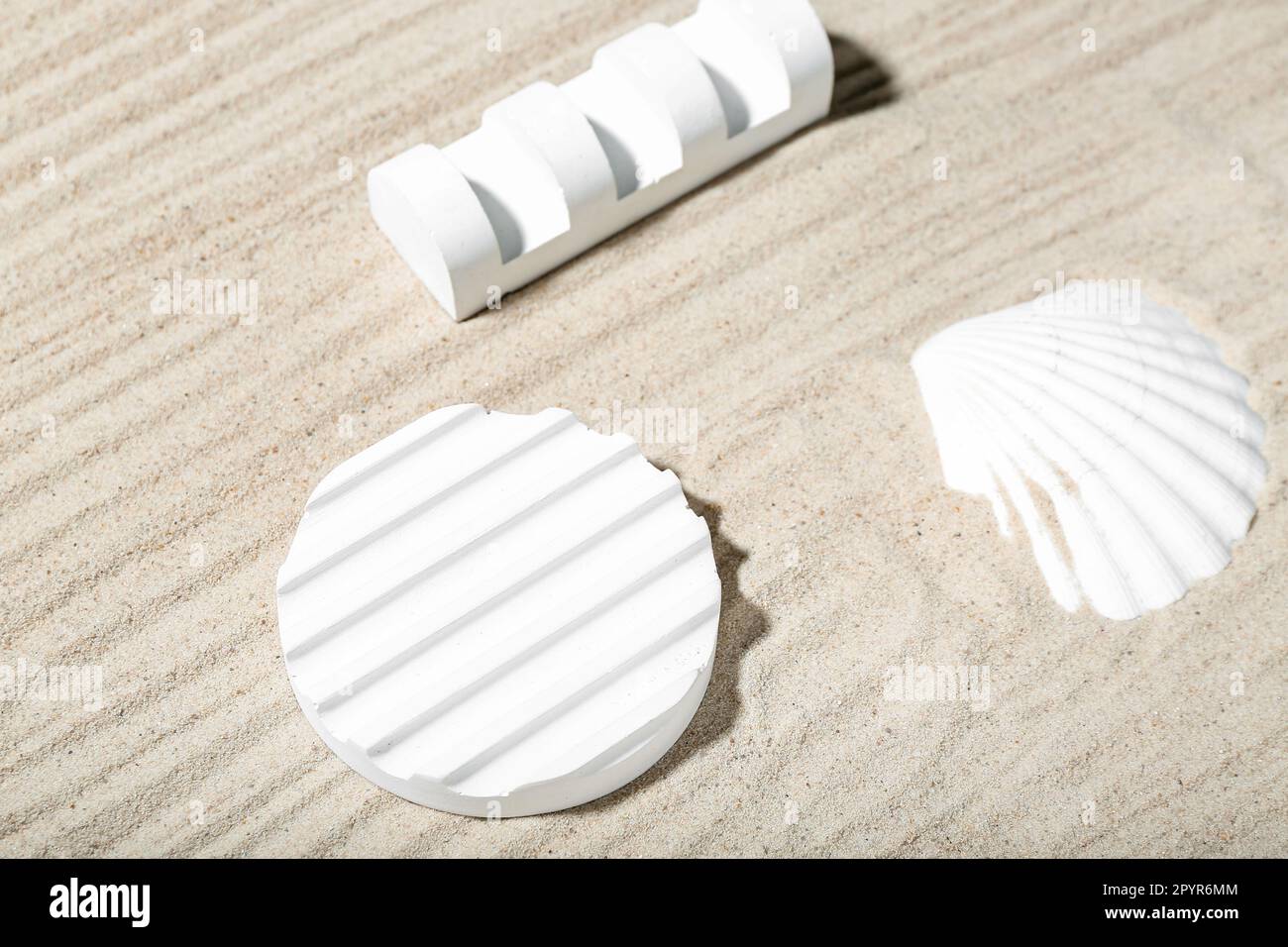 Decorative plaster podiums and seashell in sand Stock Photo - Alamy