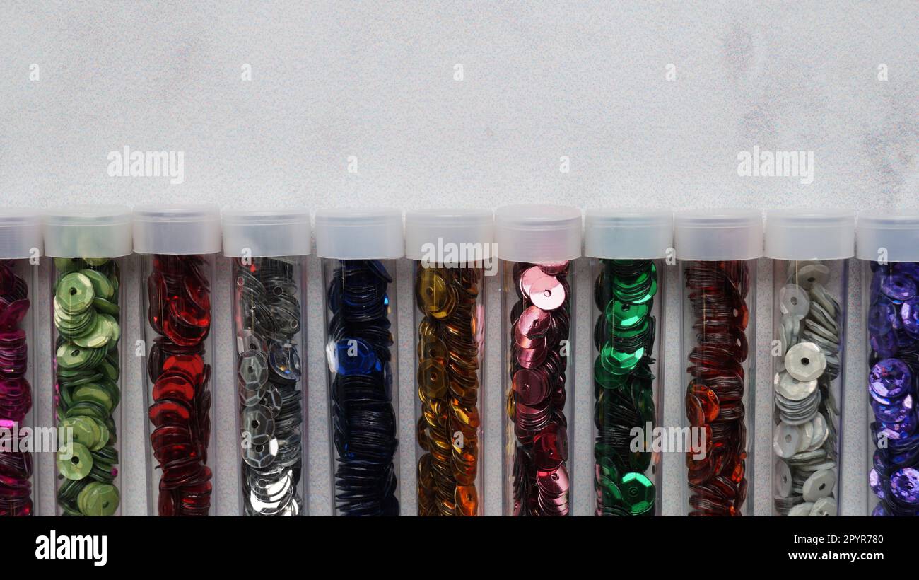 Many colorful sequins in containers on light grey background, top view ...
