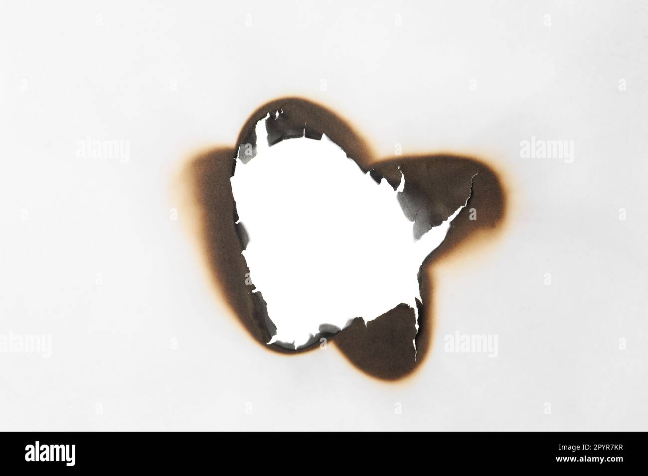 Burnt hole in paper on white background Stock Photo - Alamy