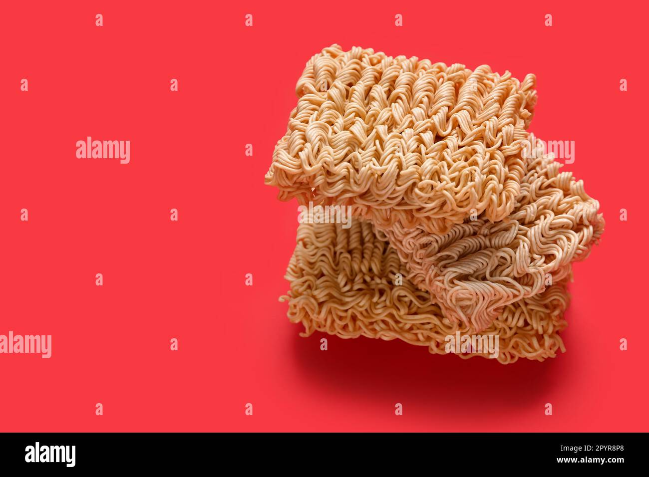 Raw instant noodles on red background Stock Photo - Alamy