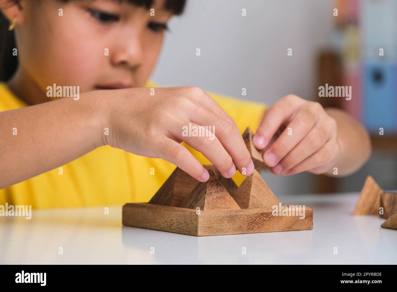 Asian cute little girl playing with wooden toy jigsaw puzzle pyramid on ...