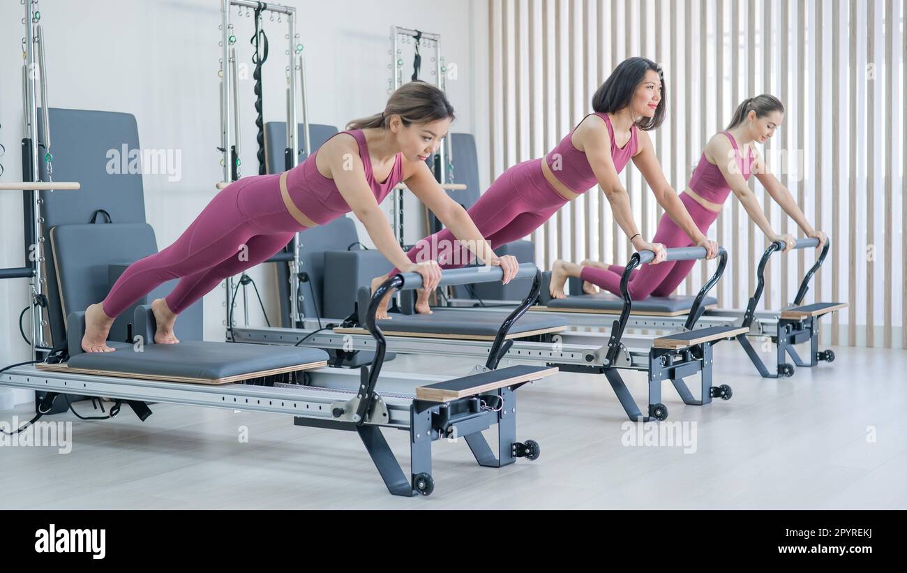 Three asian women doing plank on reformer machine Stock Photo - Alamy