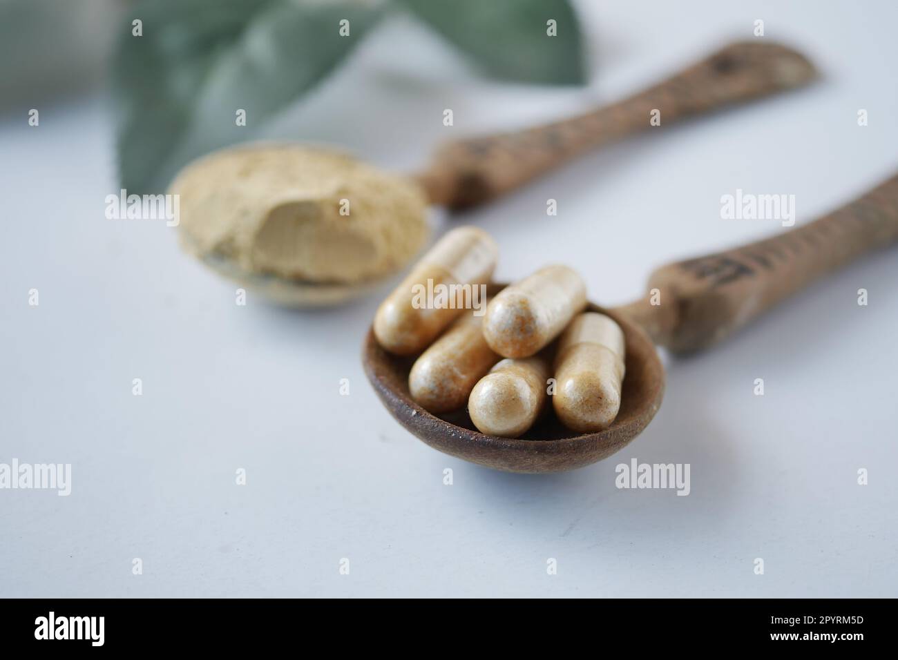 herbal medicine capsule and powder on wooden spoon on white Stock Photo ...