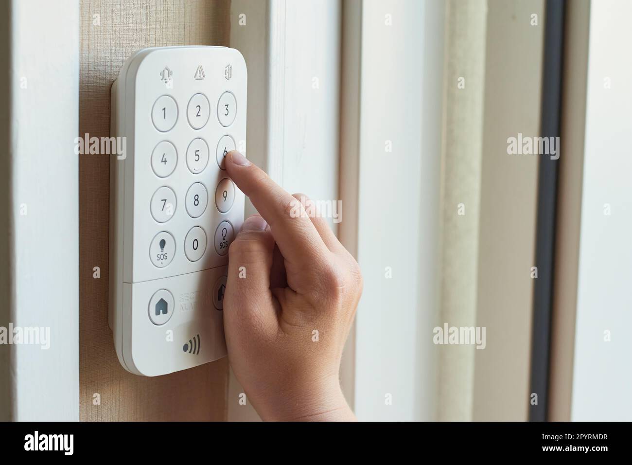 Hands of a young kid enters the code to a home security alarm on a wall ...