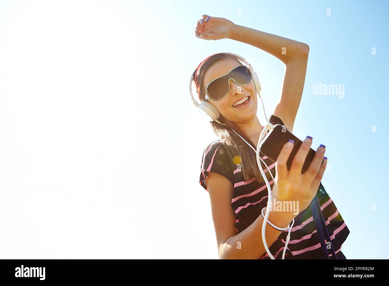 Let the music move you. A happy young teenage girl dancing outside ...