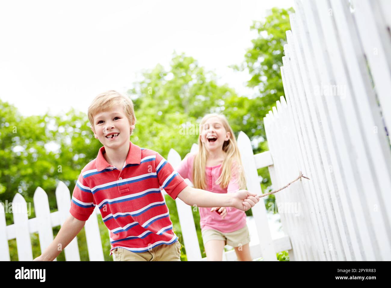 Im too fast for you. A cute young boy running a stick along a white ...
