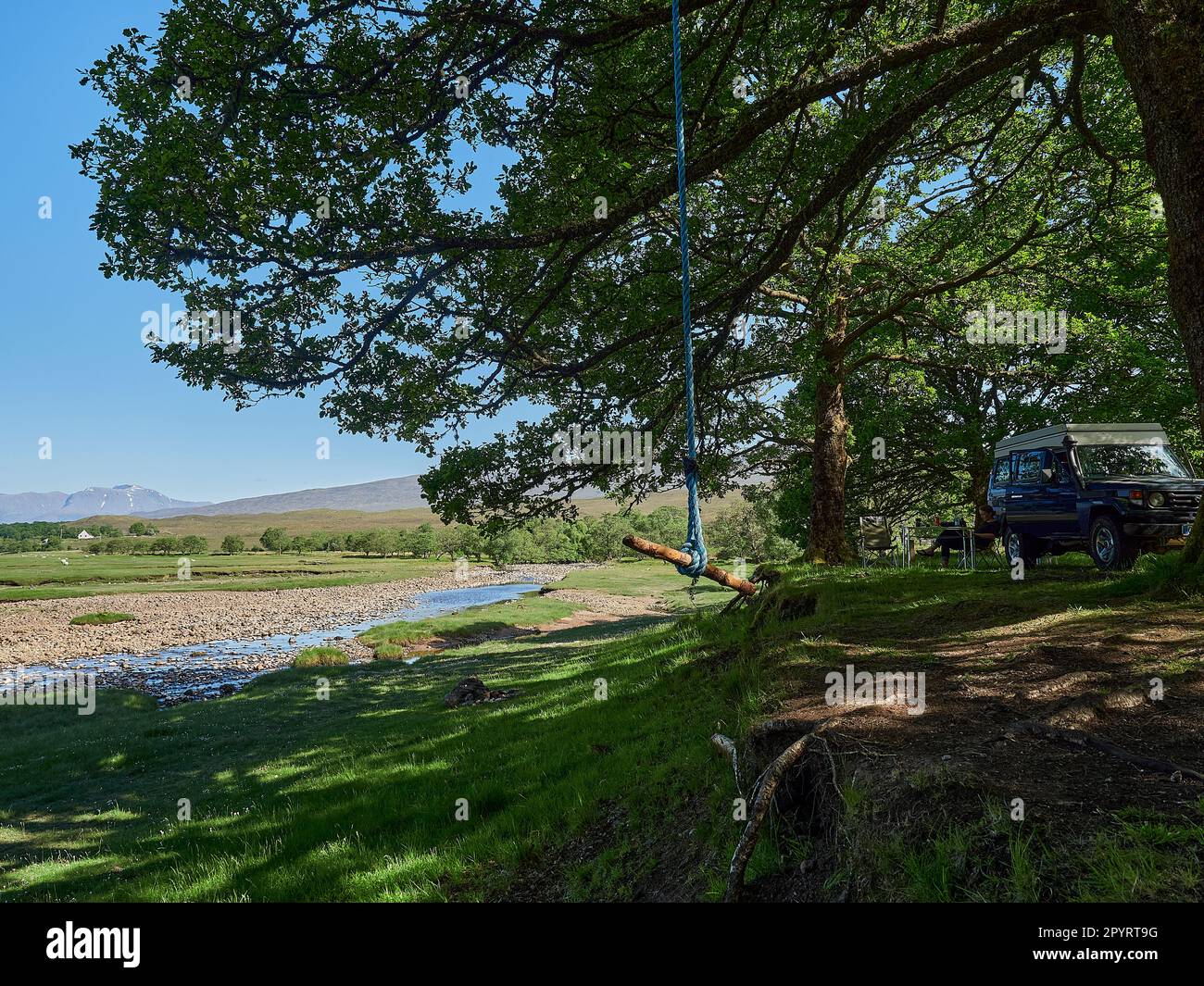 offroad vehicle parking in the shade under a lush and green tree at the ...