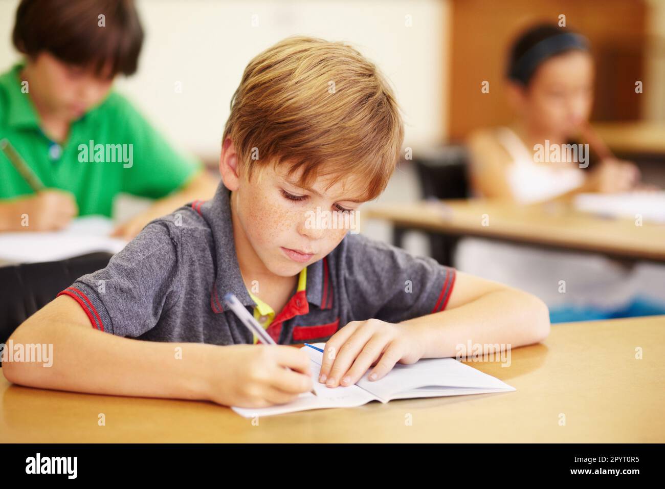 Boy kid, school classroom and writing test with focus, concentration ...
