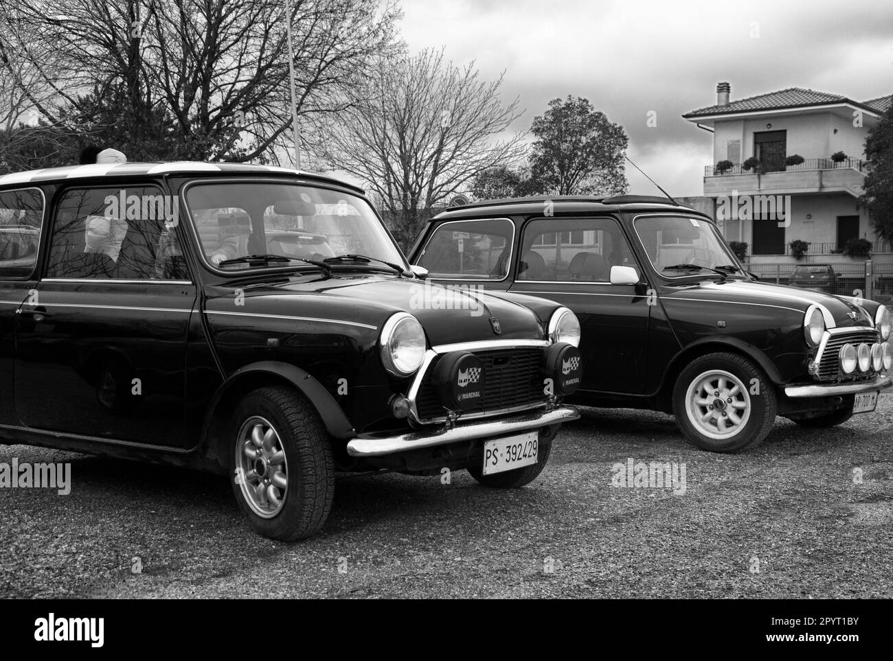 A grayscale shot of two Mini Coopers parked on the street in Italy ...