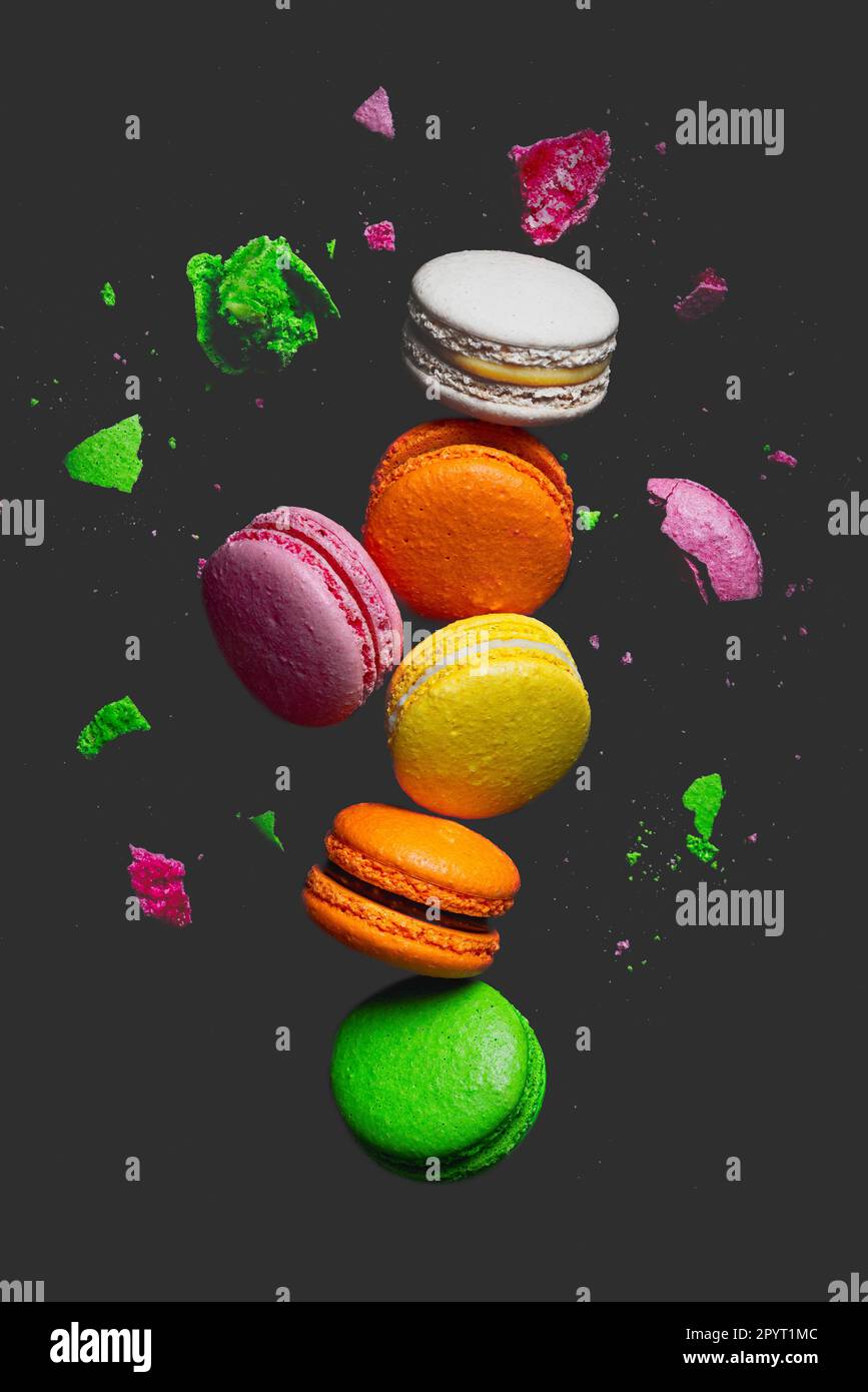 Different types of macaroons in motion falling on black background ...