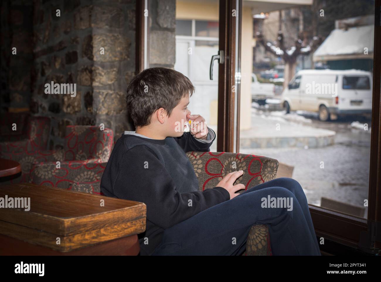 Portrait of a little boy looking out on front of the window at a cold ...