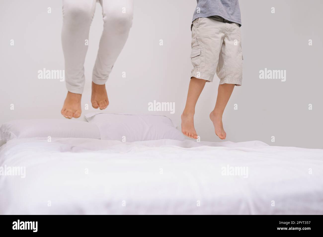 How high can you go. the legs of a little boy and girl jumping on a bed ...