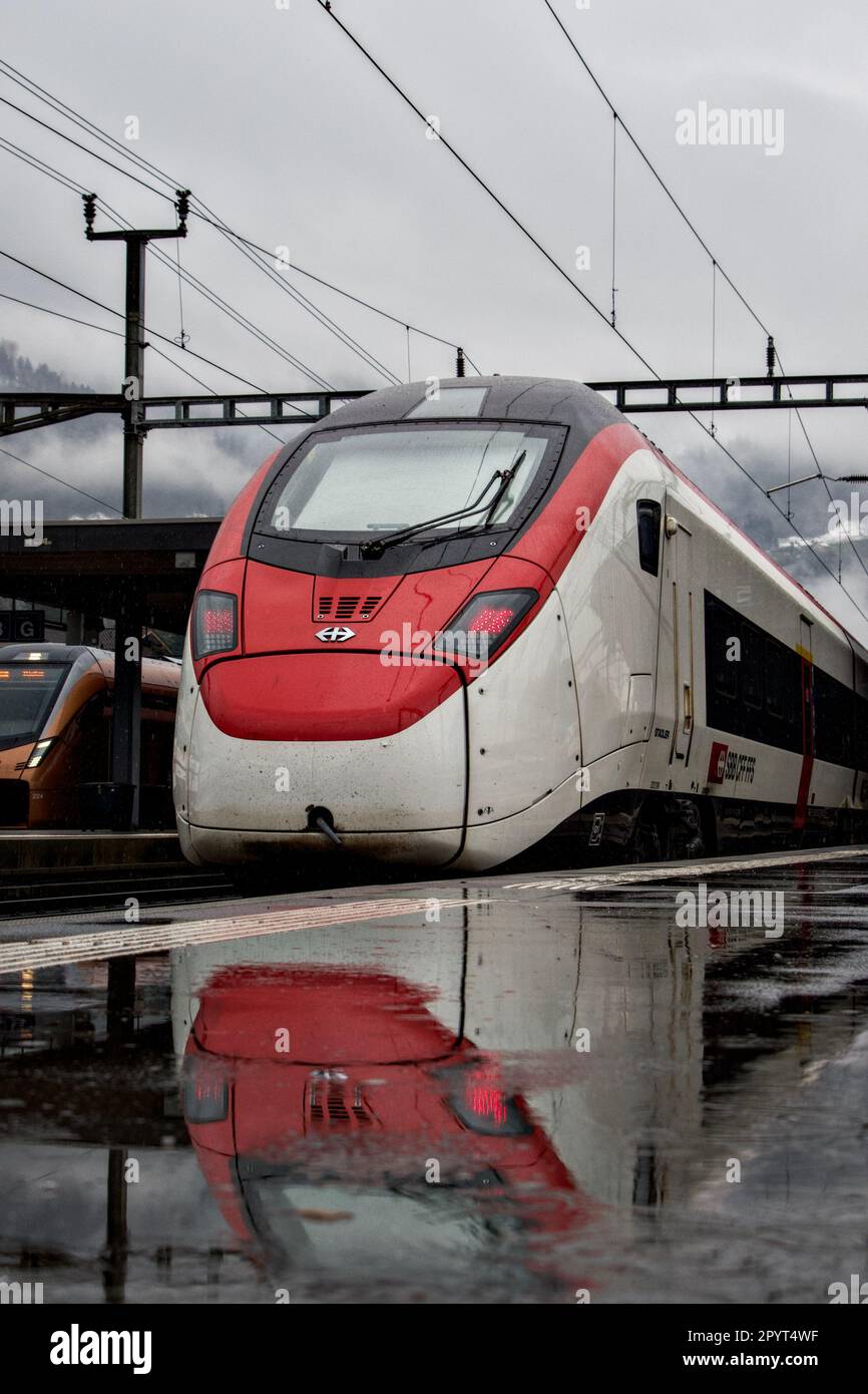 A vertical of a passenger train at the station with power lines in the ...