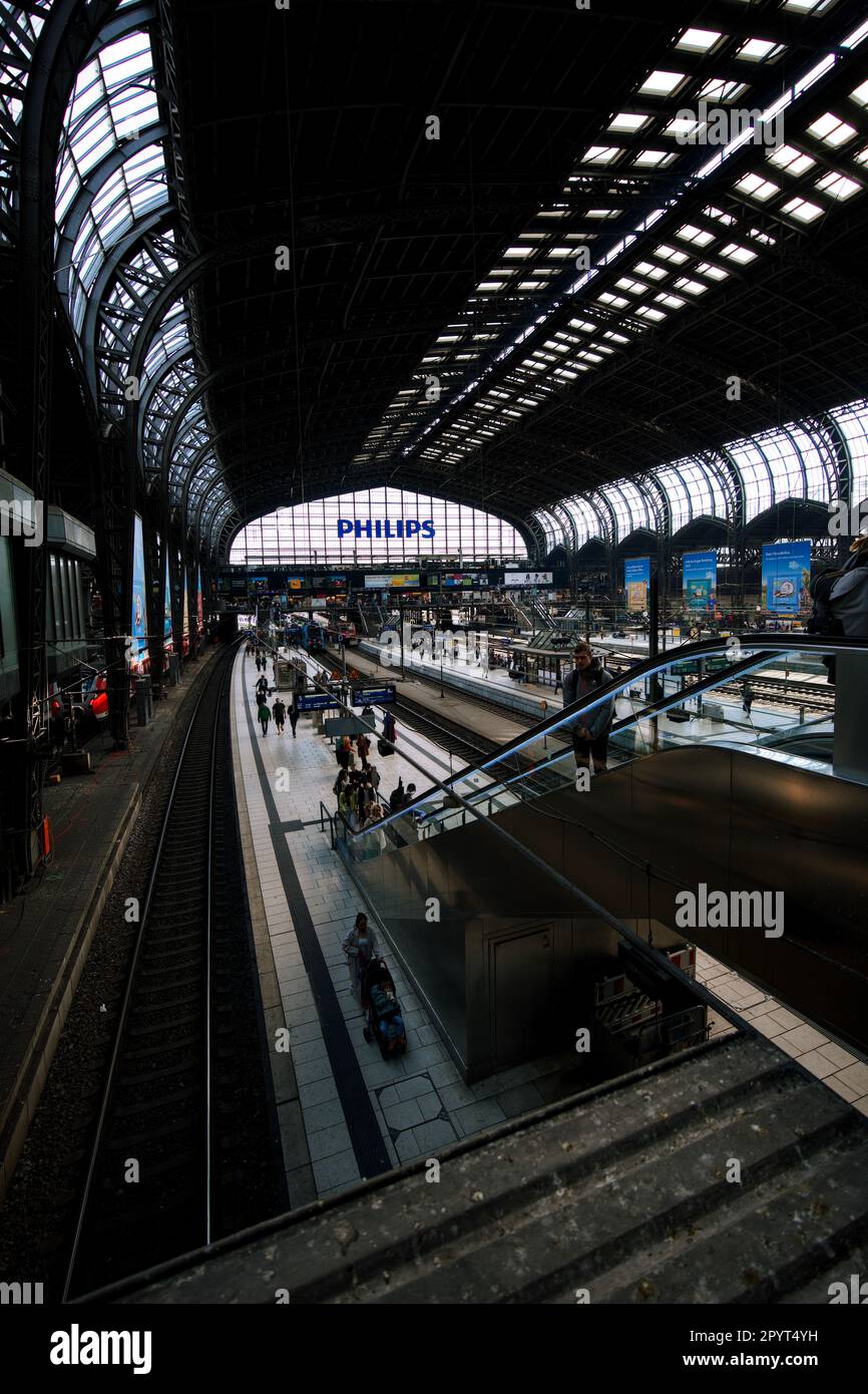 A vertical of a bustling train station with multiple platforms filled ...