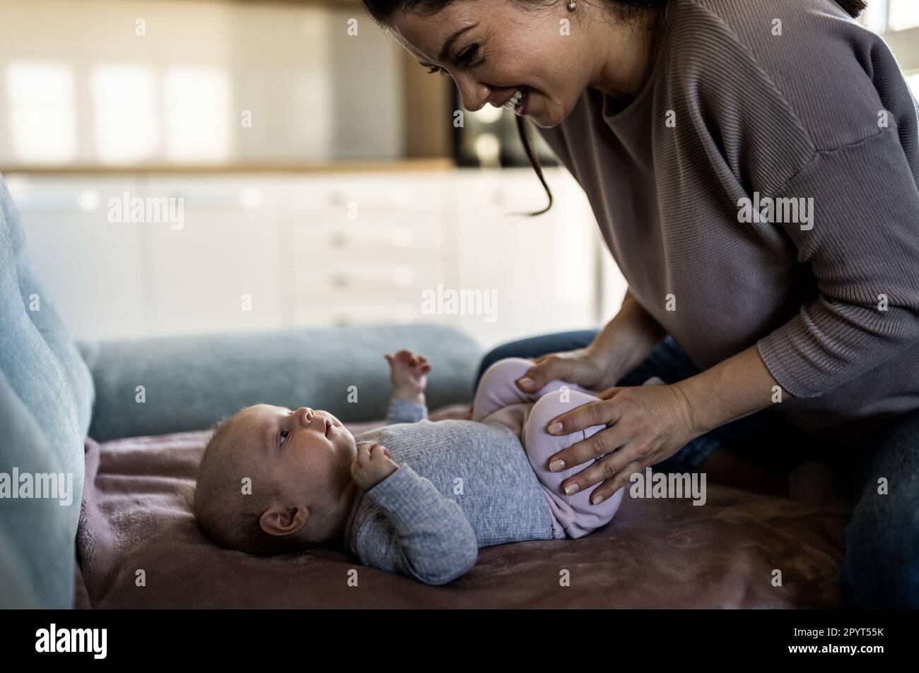 Cute newborn baby lying on back and smiling at mother on bed at home ...