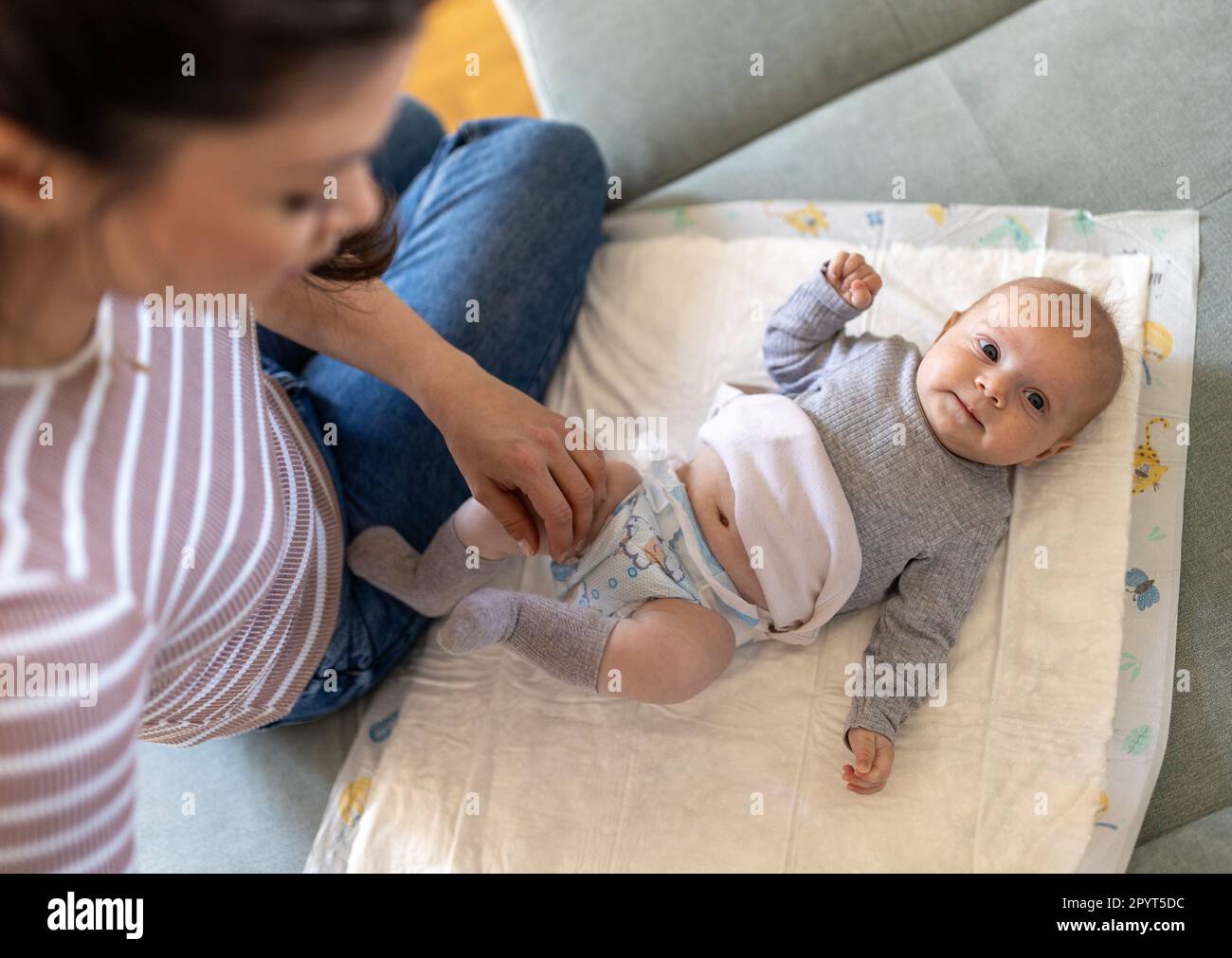 Top view of cute newborn baby lying on back on sofa while mother ...